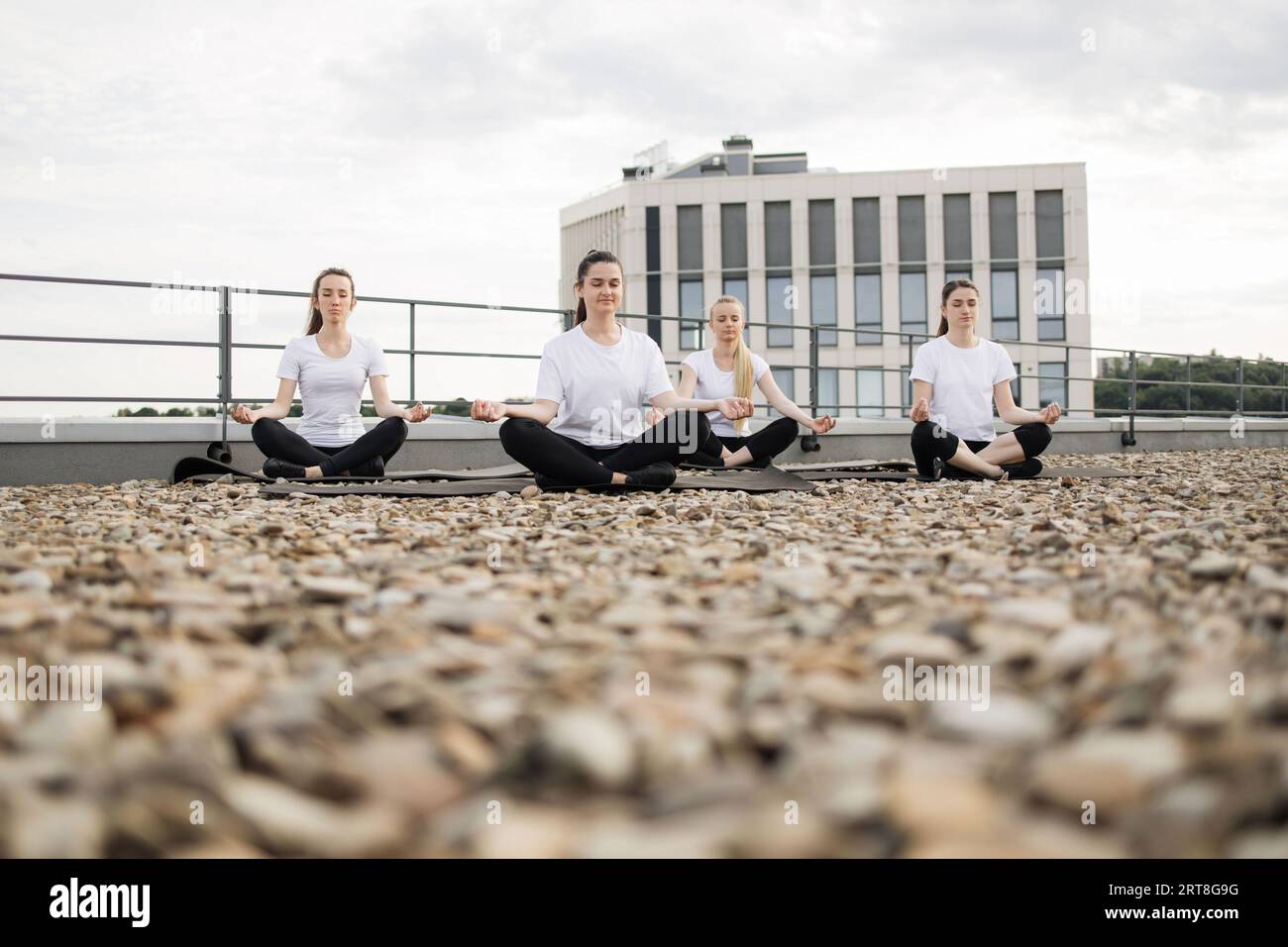 Female yoga practitioners holding lotus position outdoors Stock Photo ...