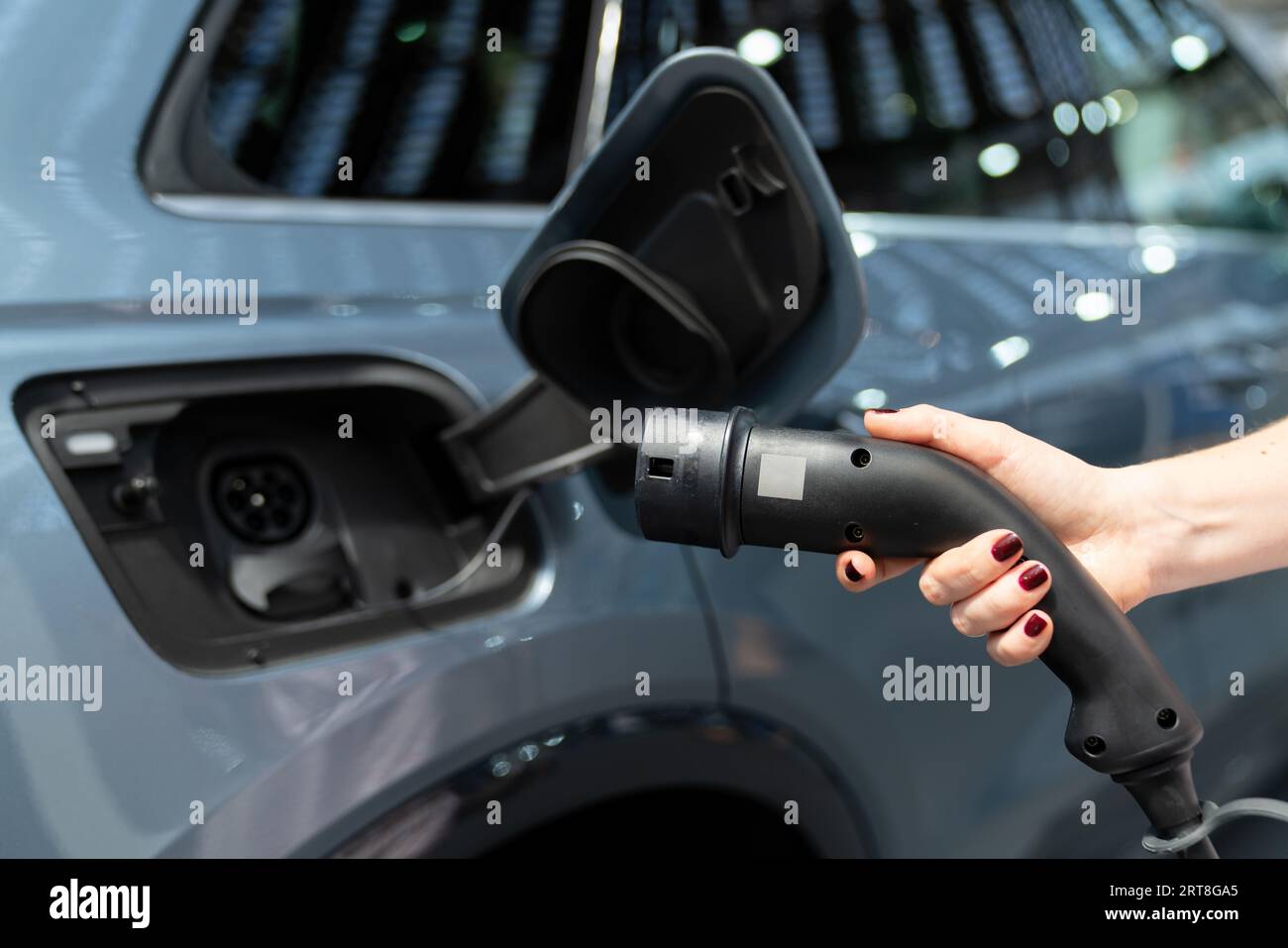Woman holding plug of electric car charging station Stock Photo - Alamy