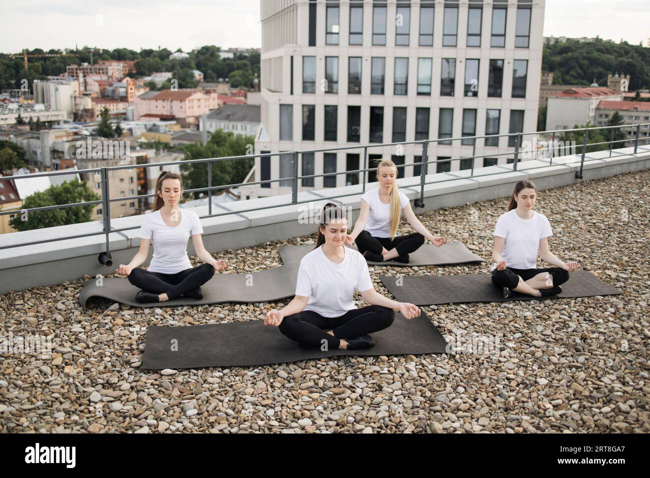 Female yoga practitioners holding lotus position outdoors Stock Photo ...