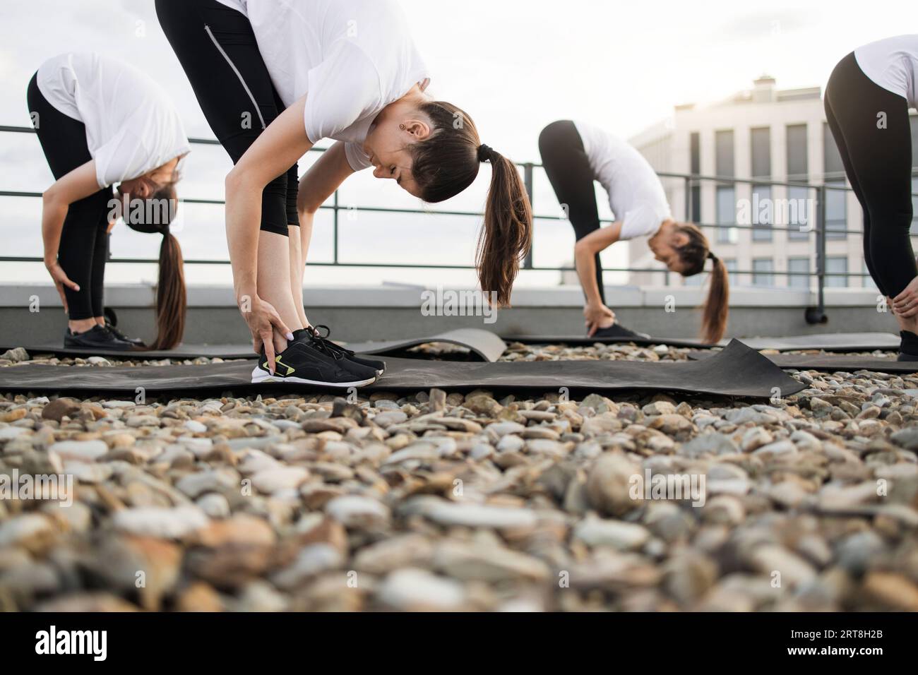 Practitioners getting into standing yoga pose on rooftop Stock Photo ...