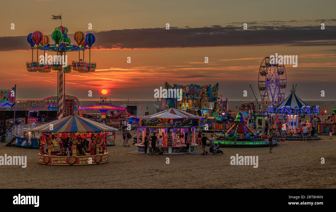 brightly lit funfair with rides on the beach in front of a beautiful ...