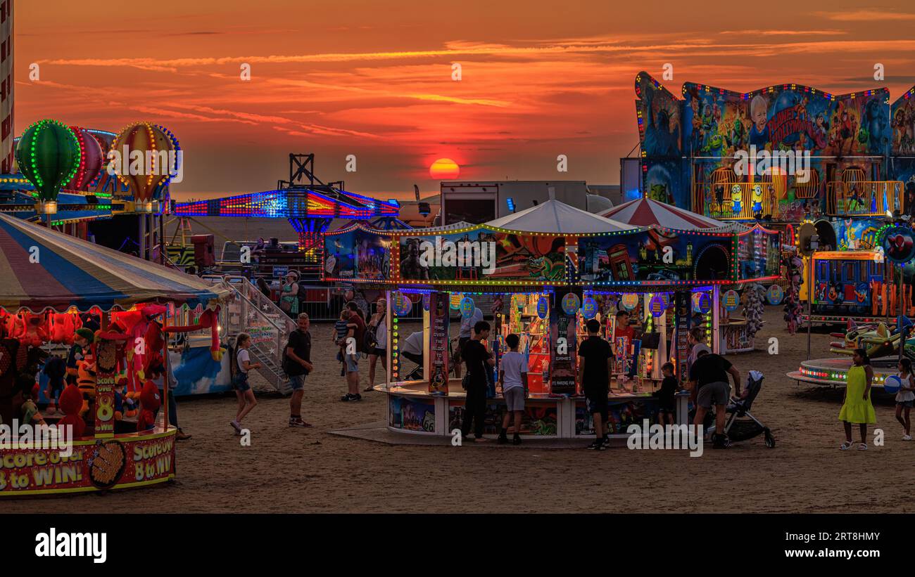 brightly lit funfair with rides on the beach in front of a beautiful ...