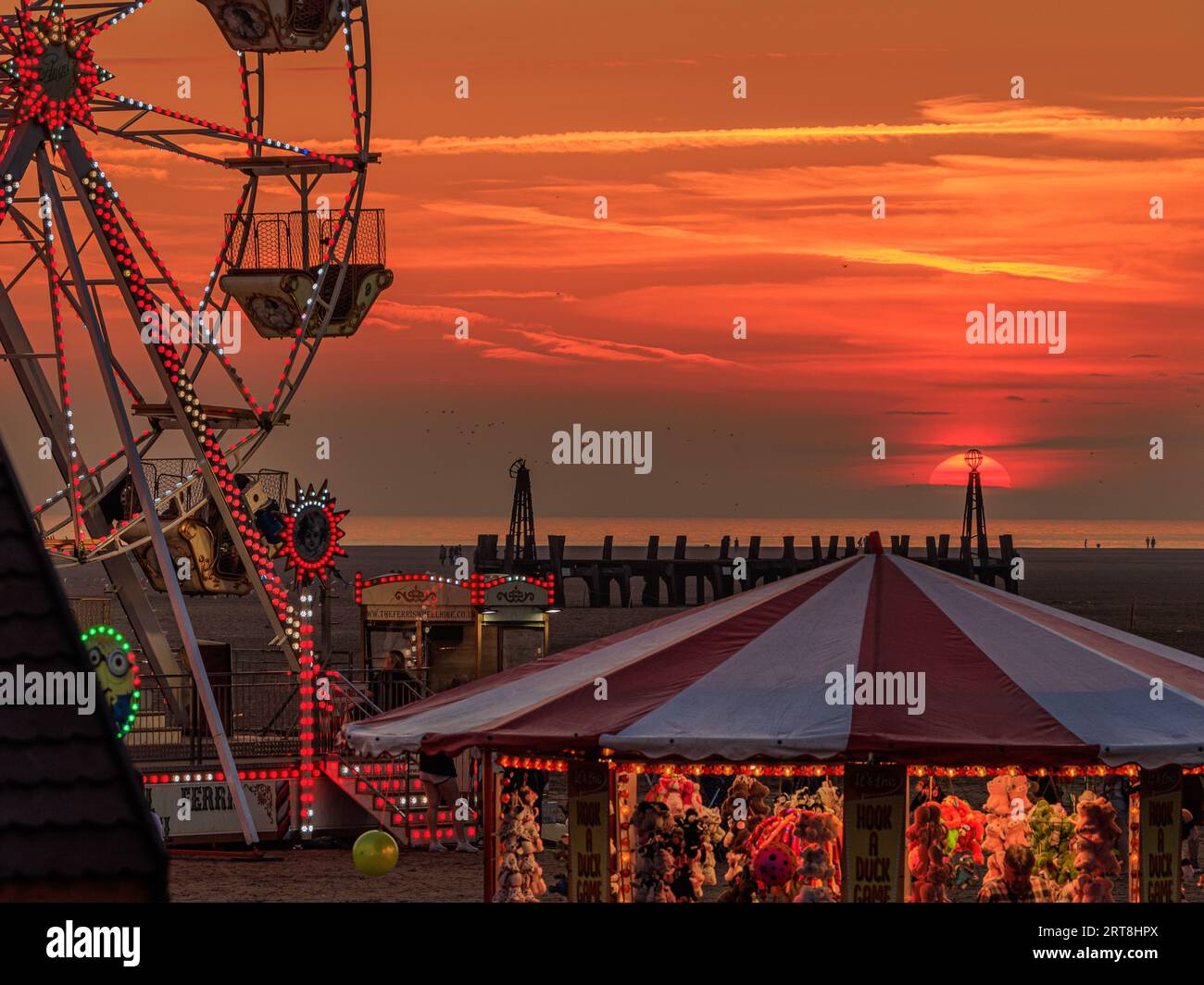 brightly lit funfair with rides on the beach in front of a beautiful ...