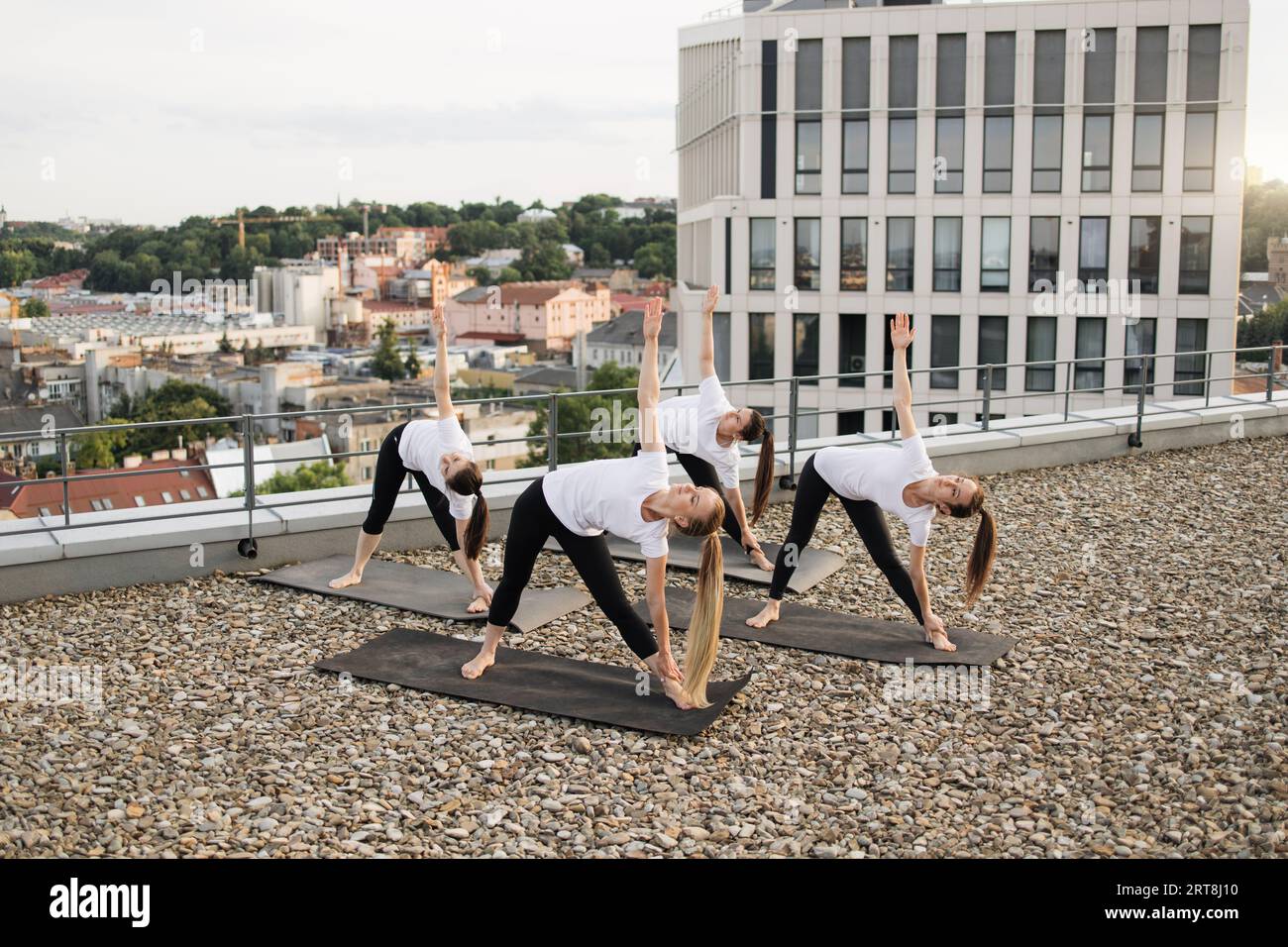 Female yoga practitioners exercising asana on open terrace Stock Photo ...