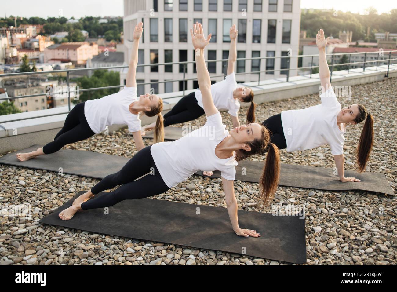 Yoga enthusiasts achieving Side Plank Pose in outdoor class Stock Photo ...