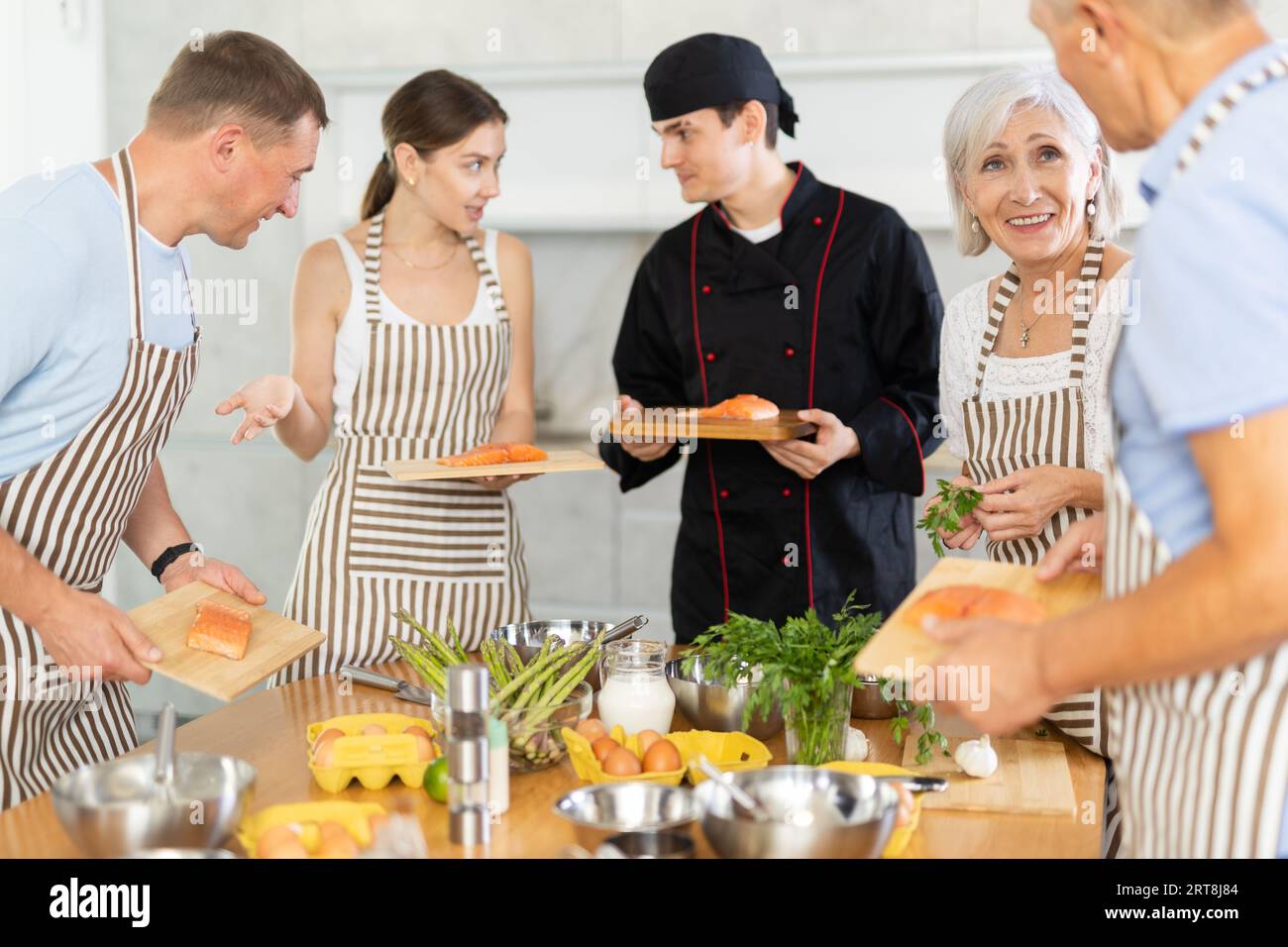 Chef in uniform teaches cooking class students how to clean and cut ...