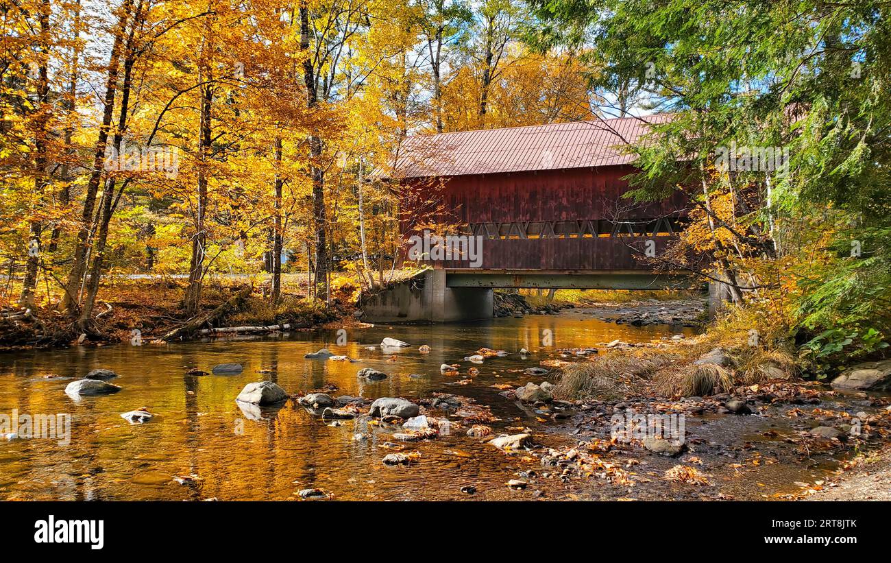 Red, wooden, covered bridge with beautiful autumn colors and river ...