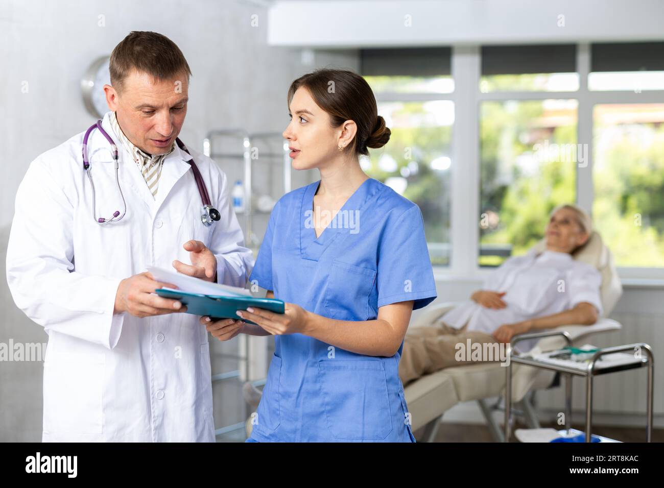 Experienced doctor advising female colleague about diagnosis of patient ...