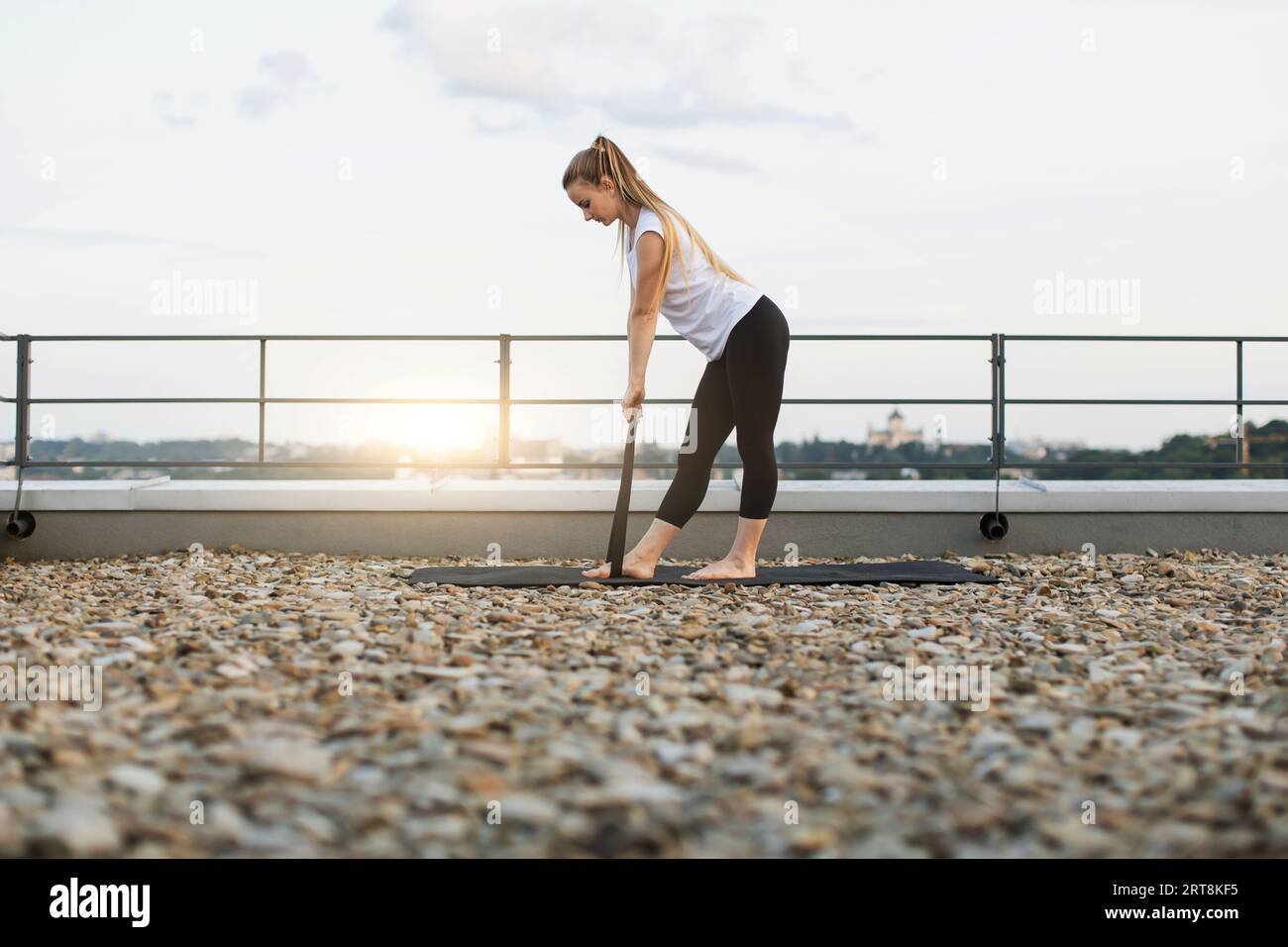 Female with stretch band working out on mat outdoors Stock Photo - Alamy