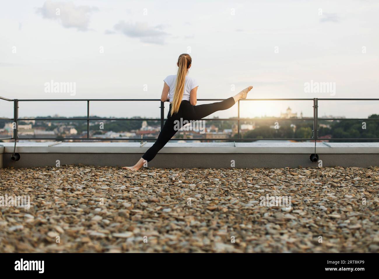Female doing split on handrail of roof in summer evening Stock Photo ...