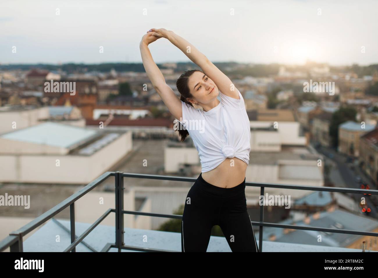 Young person raising hands in stretches on city background Stock Photo ...