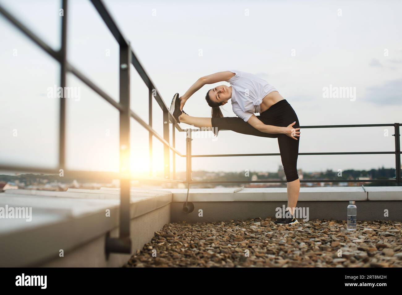 Adult person using handrail for side-bend stretch at sunset Stock Photo ...