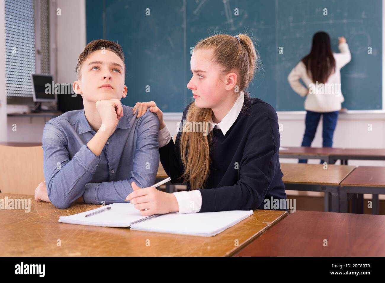 Thoughtful young students during writing notes in classroom Stock Photo ...