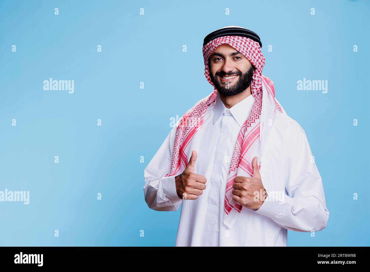Arab man wearing islamic clothes giving thumbs up and showcasing ...