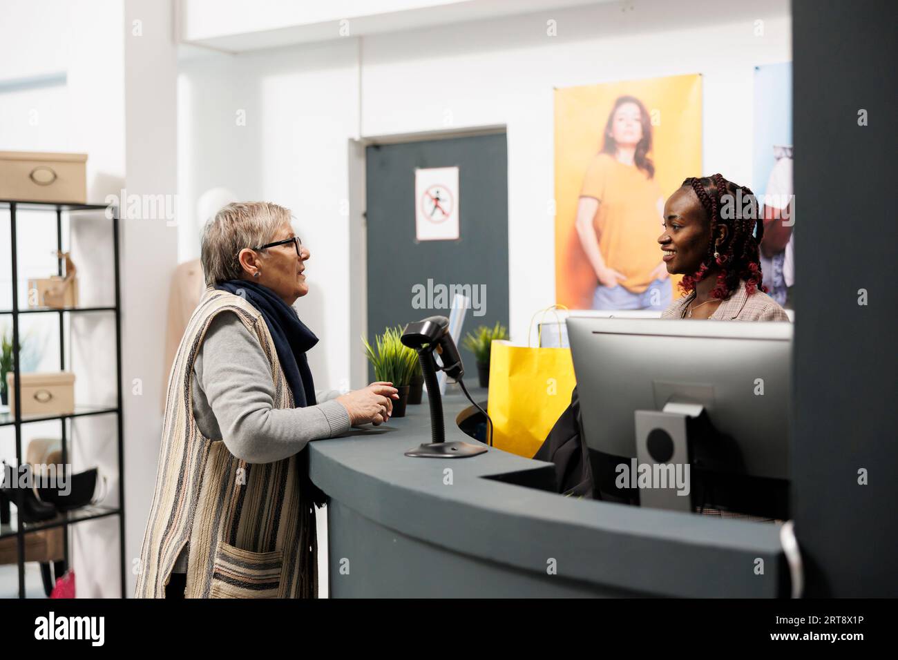 Elderly customer discussing with clothing store employee at cash ...