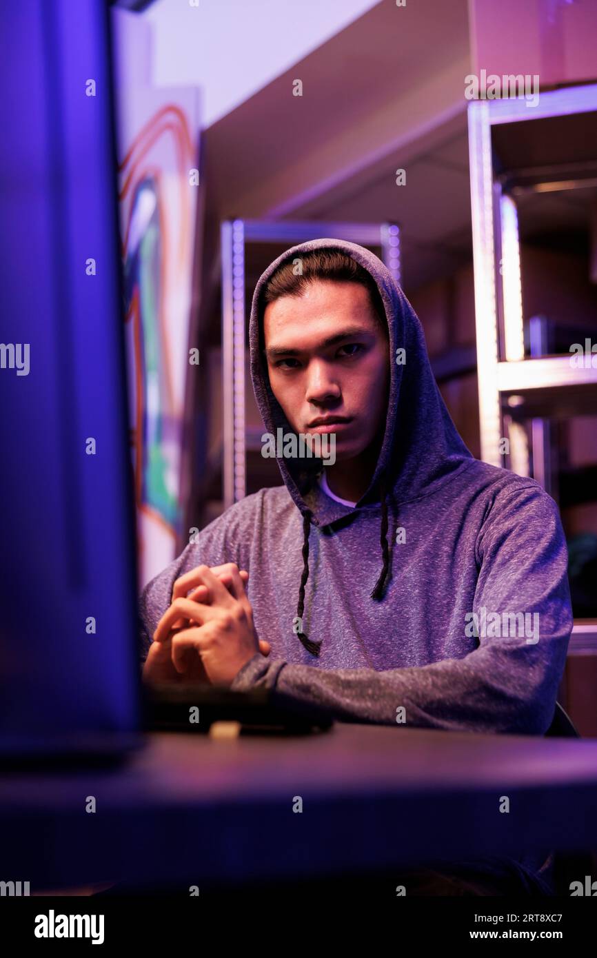 Serious hacker developing malicious software and looking at camera ...