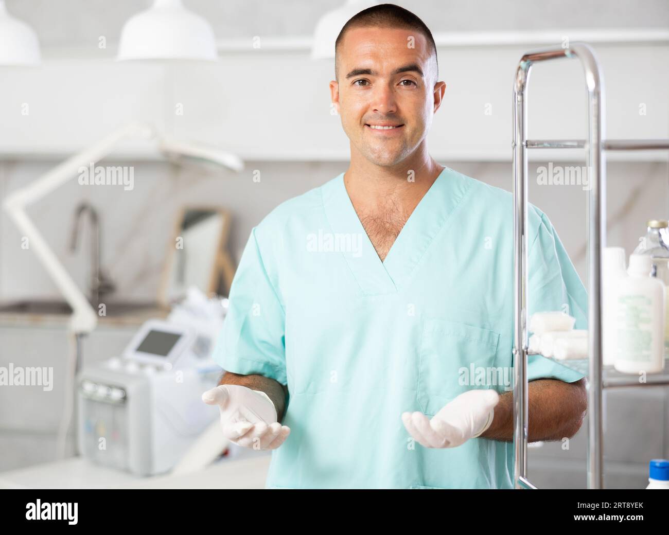 Portrait of male doctor cosmetologist wearing overall showing equipment ...