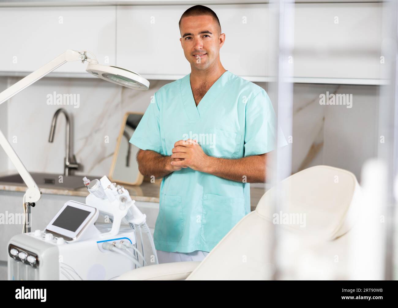 Portrait of male doctor cosmetologist wearing overall showing equipment ...