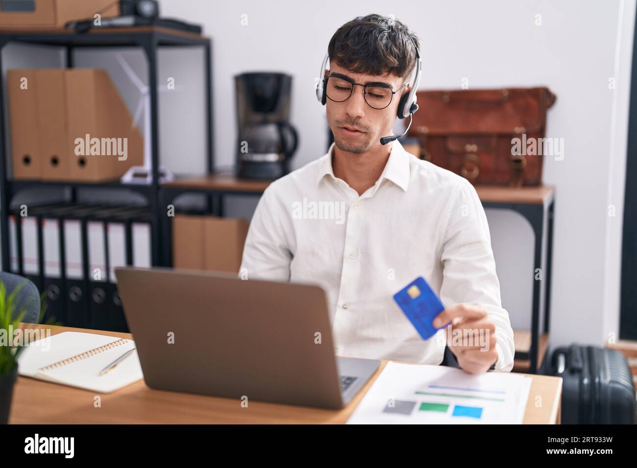 Young hispanic man working using computer laptop holding credit card ...