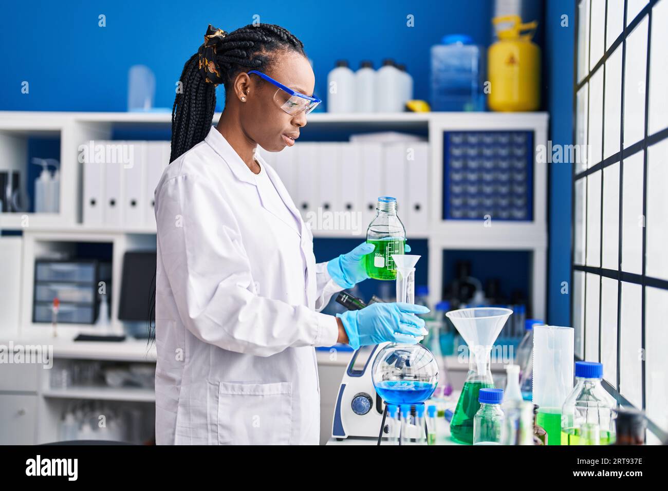 African american woman scientist pouring liquid on test tube at ...