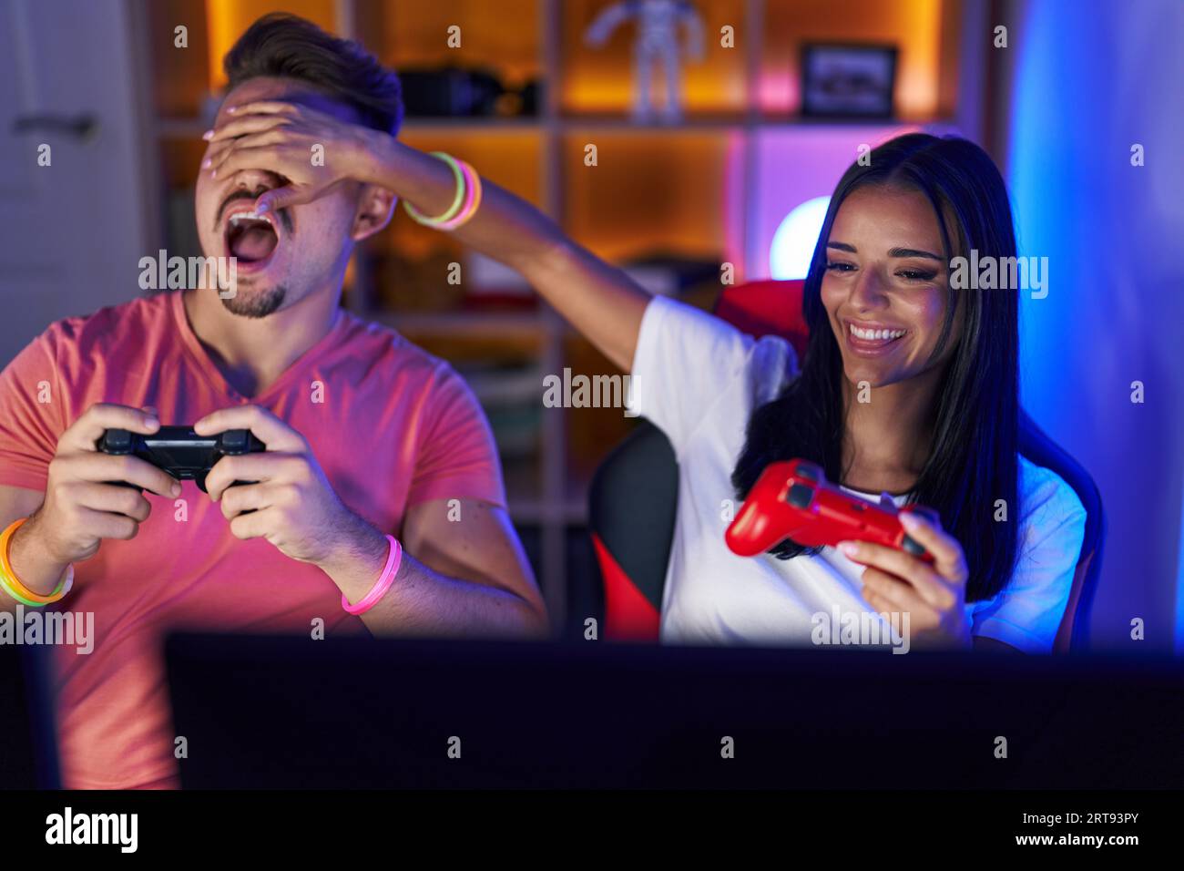 Man and woman streamers playing video game using computer and joystick ...