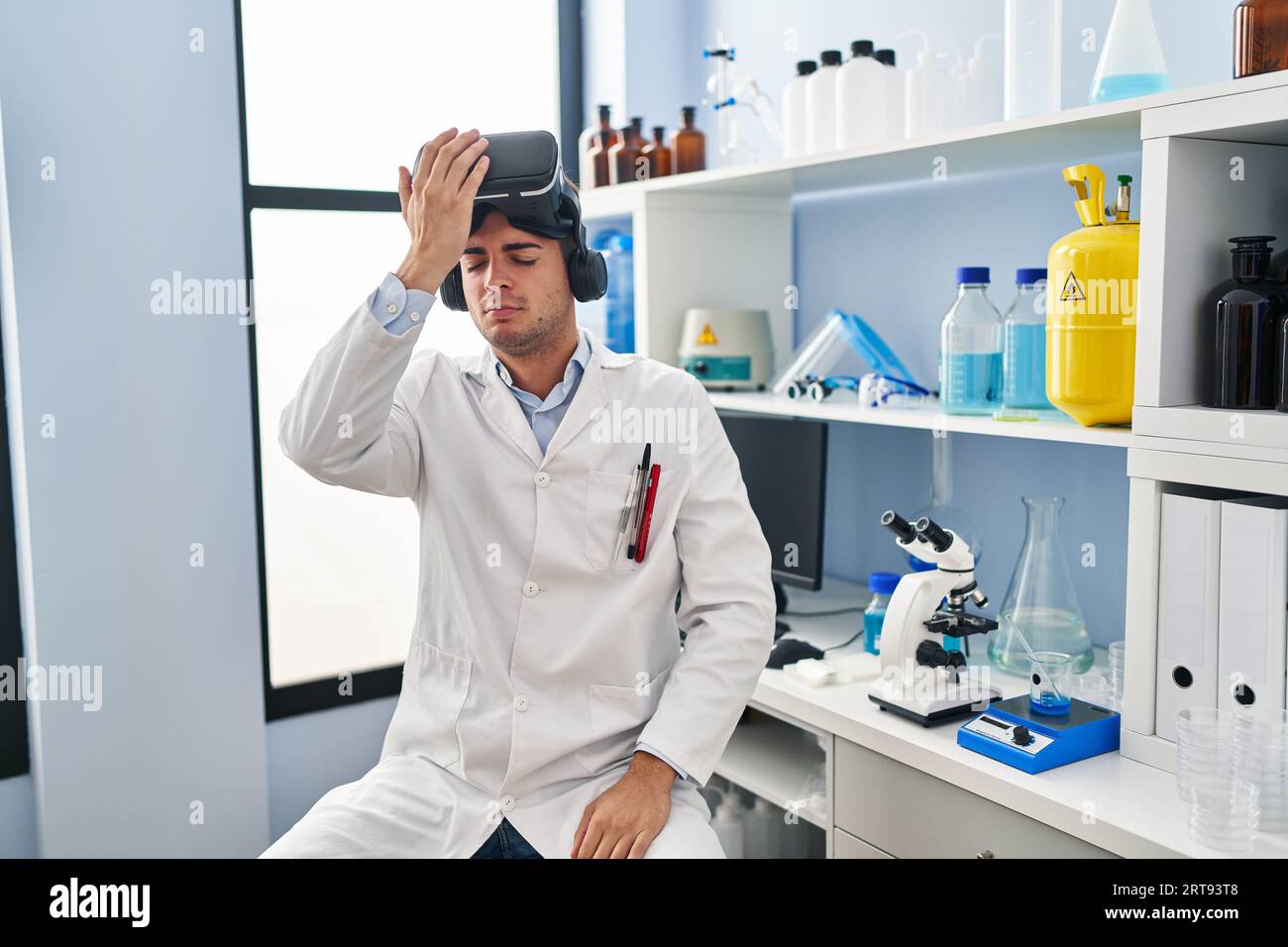 Young hispanic man working at scientist laboratory wearing vr glasses ...