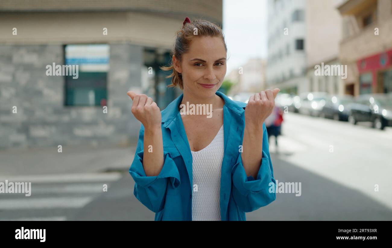 Young woman smiling confident doing spend money gesture at street Stock ...