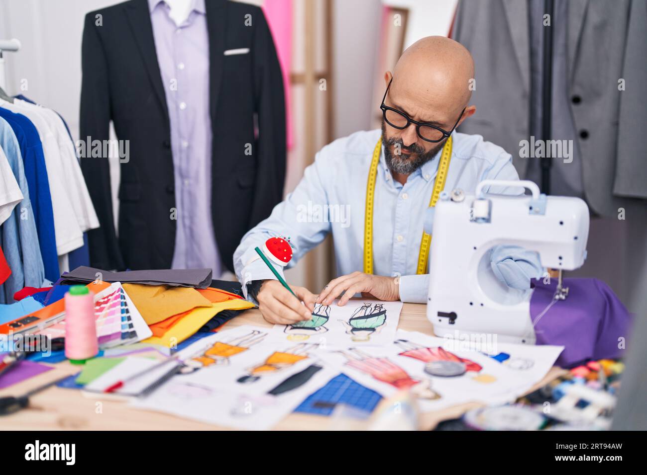 Young bald man tailor drawing clothing design at tailor shop Stock ...