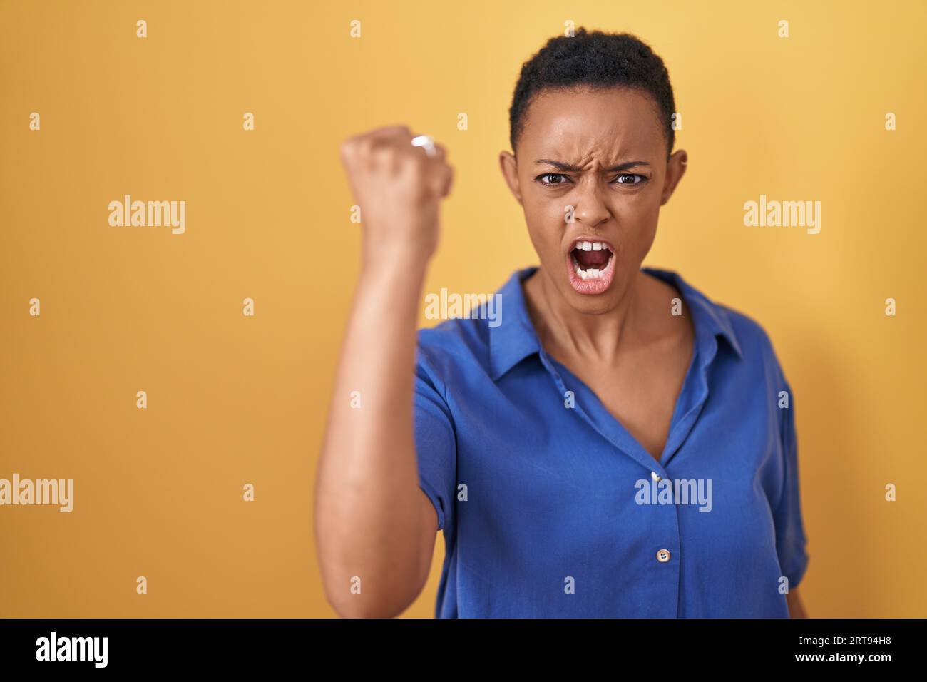 African american woman standing over yellow background angry and mad ...