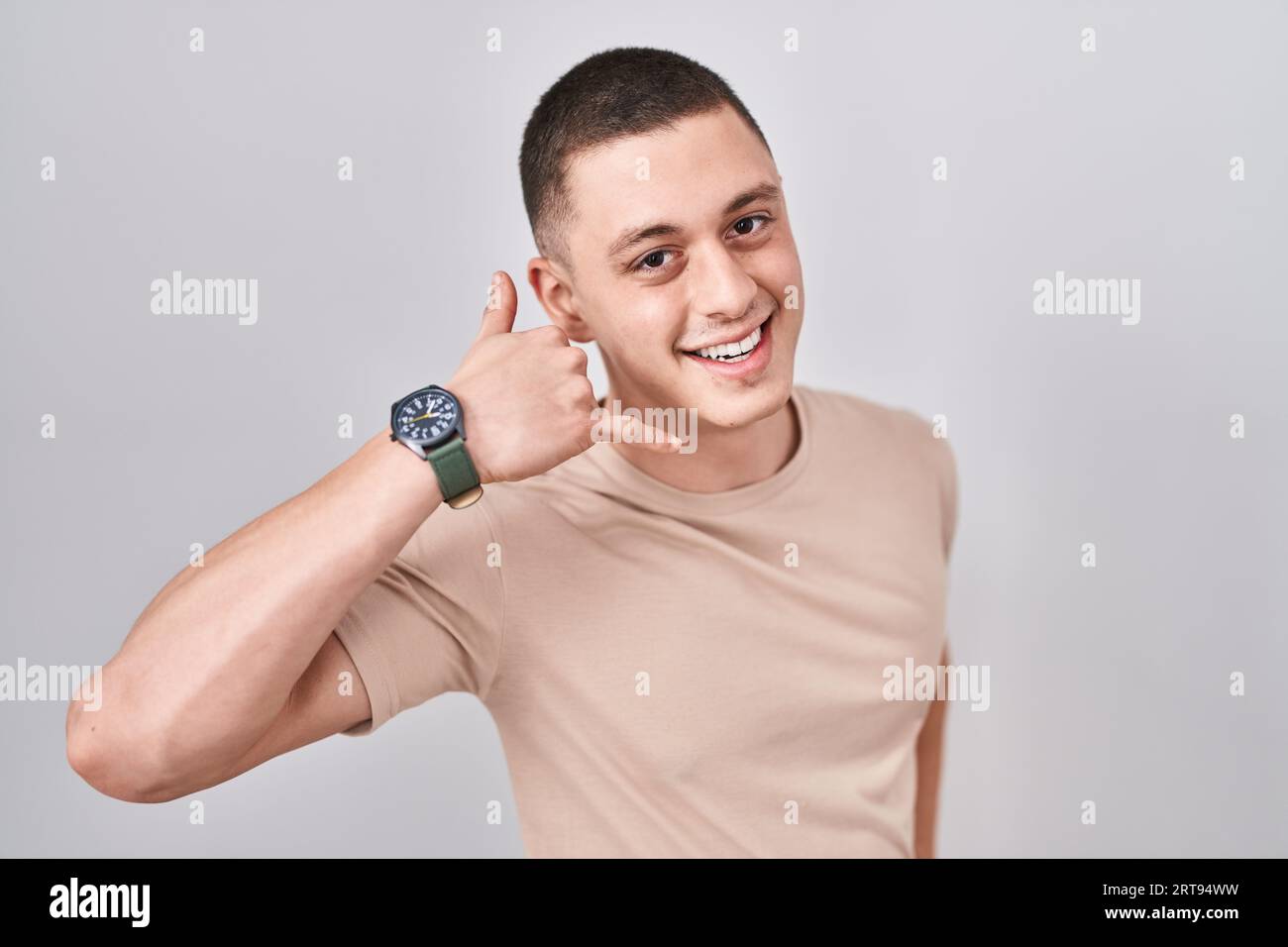 Young man standing over isolated background smiling doing phone gesture ...