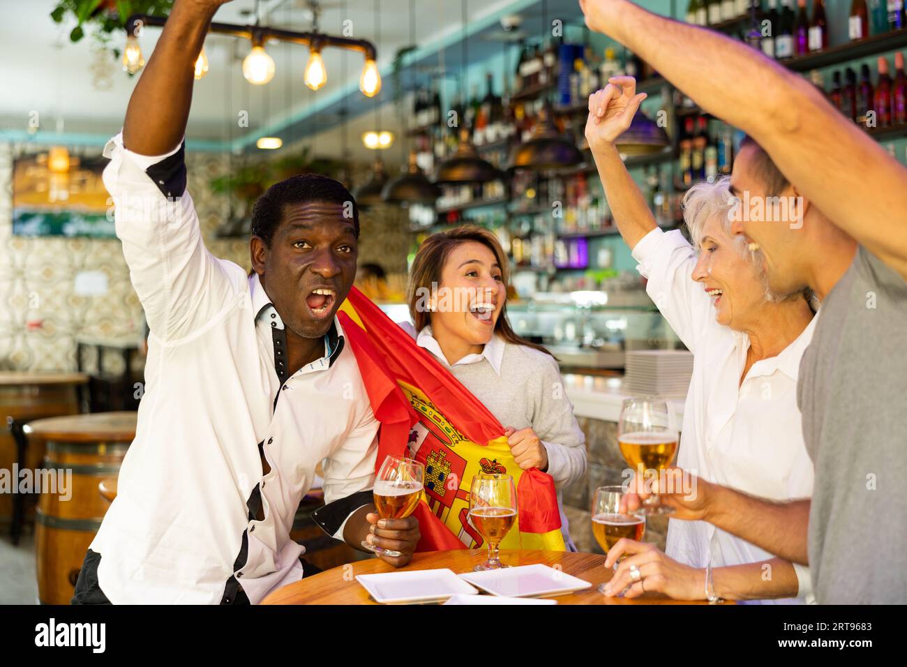 Family watching sports match on tv at pub, cheering and shouting goal ...
