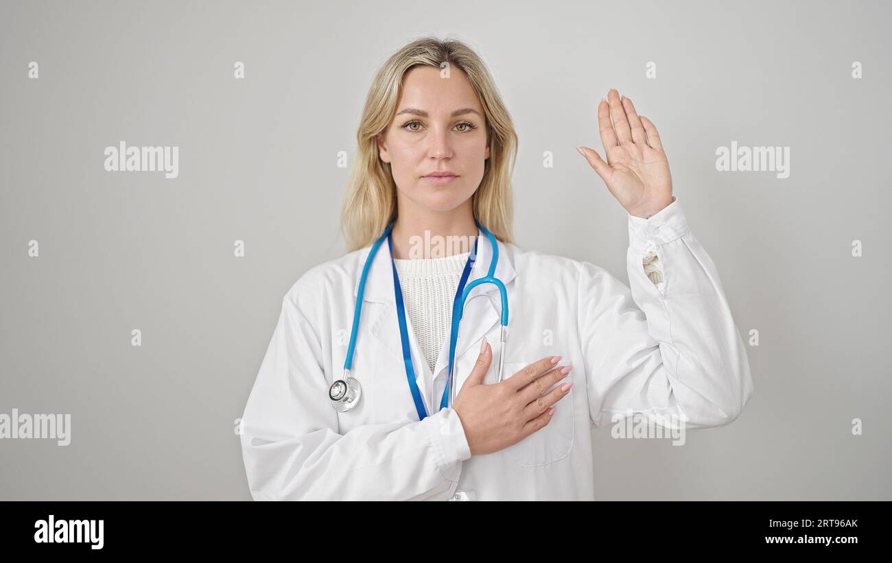 Young blonde woman doctor making an oath with hand on chest over ...