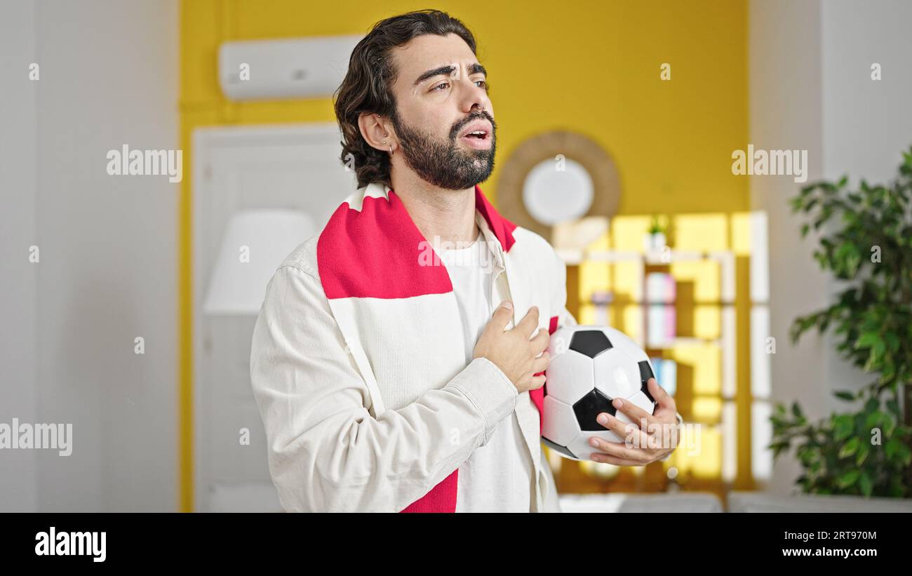 Young hispanic man singing soccer team anthem with hand on heart ...