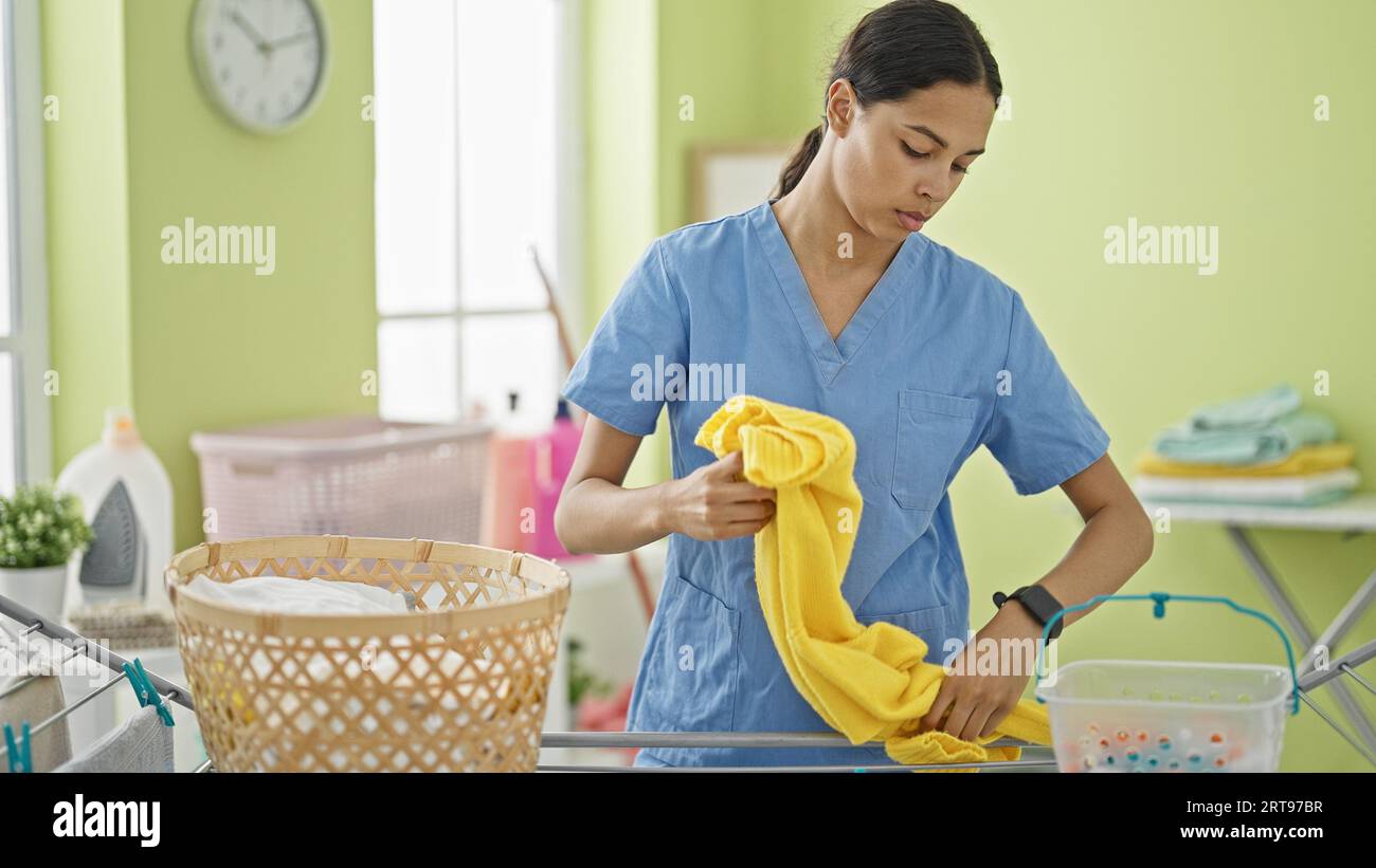 African american woman professional cleaner hanging clothes on ...