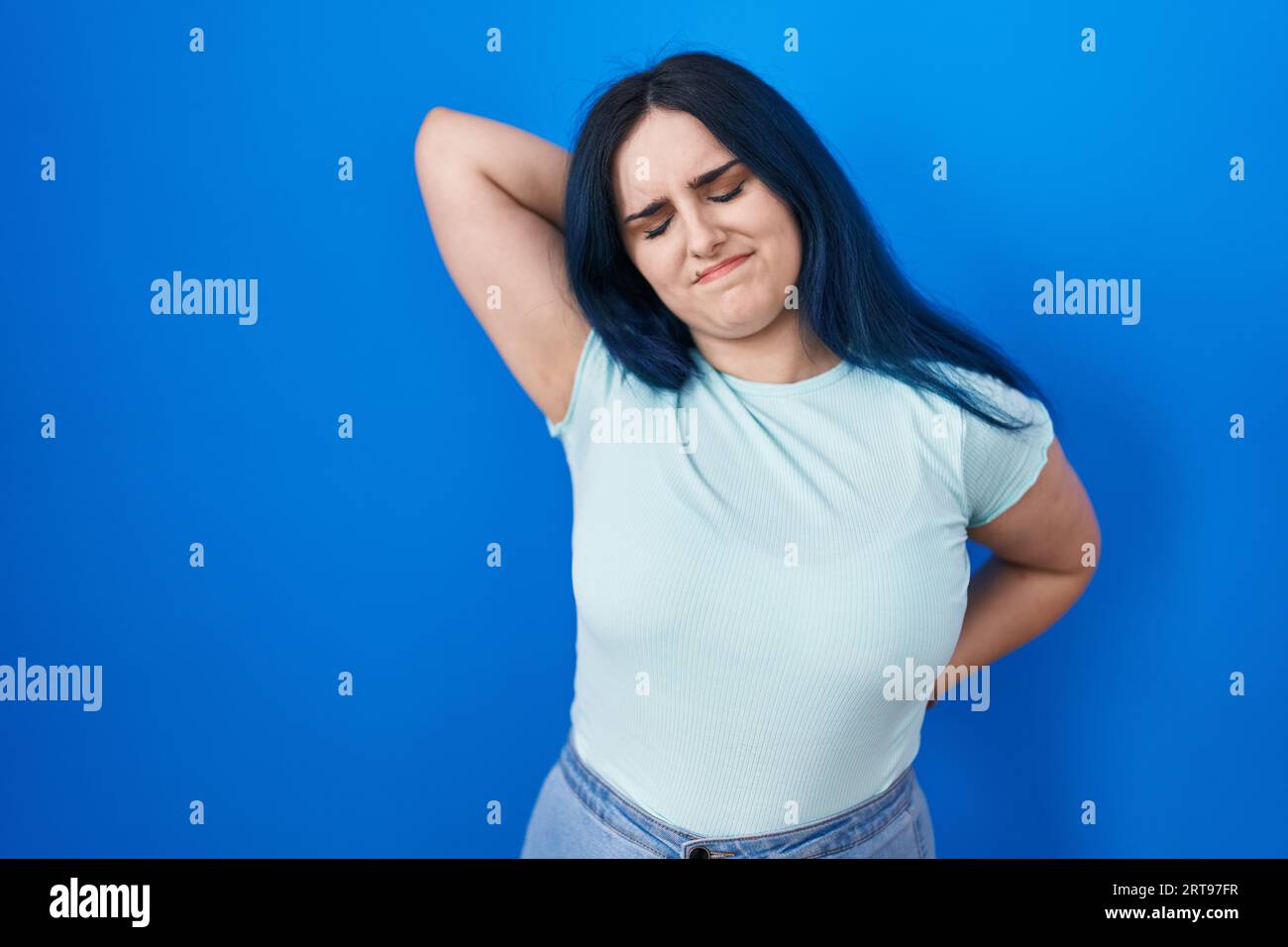 Young modern girl with blue hair standing over blue background ...