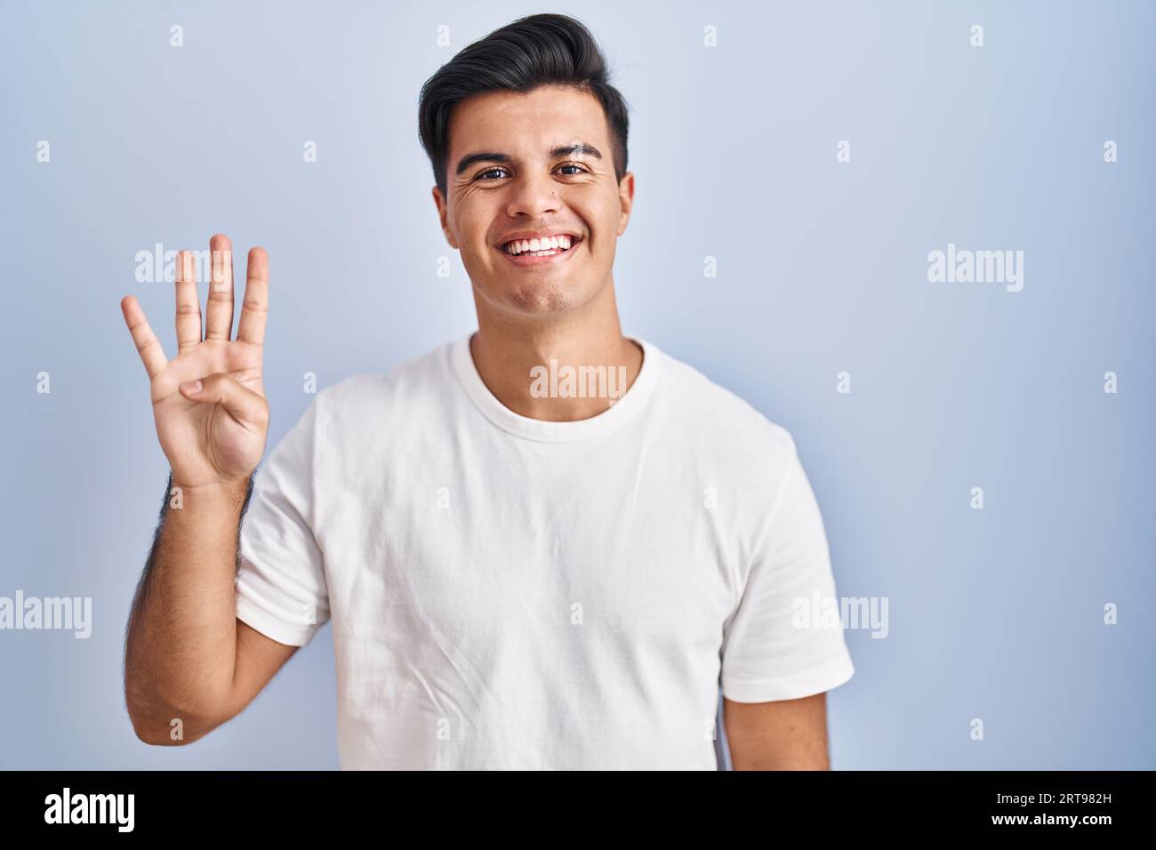 Hispanic man standing over blue background showing and pointing up with ...