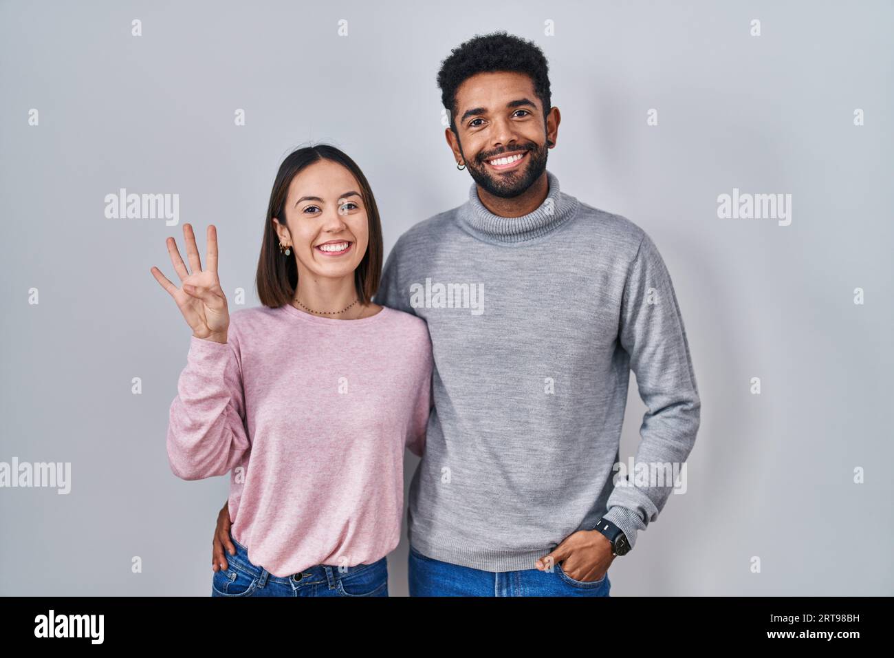 Young hispanic couple standing together showing and pointing up with ...