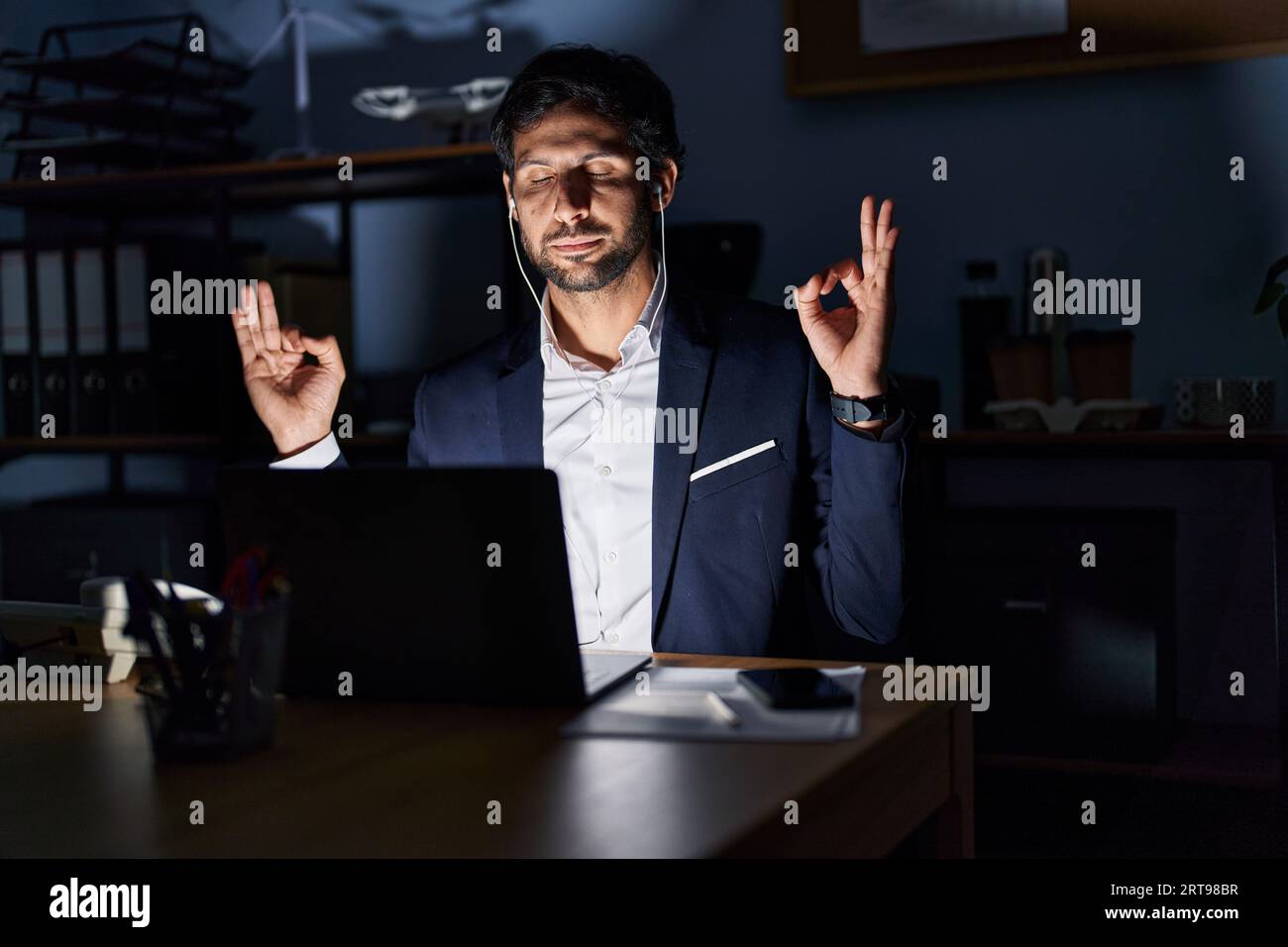 Handsome latin man working at the office at night relax and smiling ...