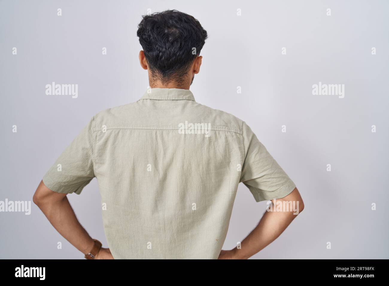 Arab man with beard standing over white background standing backwards ...
