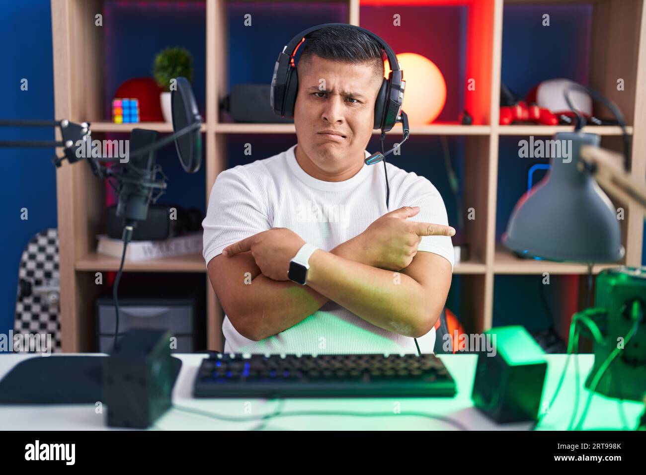 Young hispanic man playing video games pointing to both sides with ...