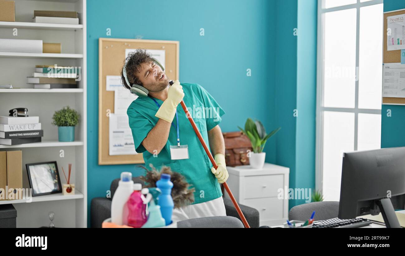 Young hispanic man professional cleaner singing song dancing at office ...