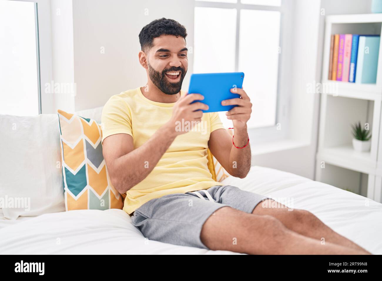 Young arab man watching video on touchpad sitting on bed at bedroom Stock Photo - Alamy
