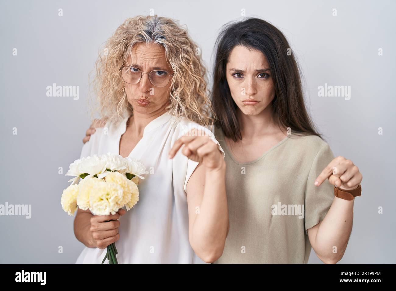 Mother and daughter holding bouquet of white flowers pointing down ...