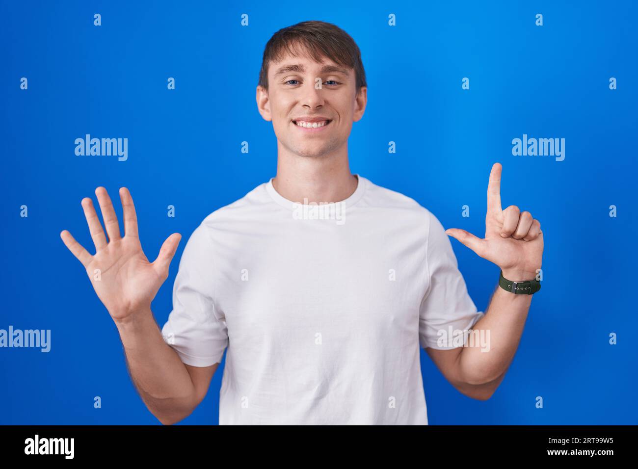 Caucasian blond man standing over blue background showing and pointing ...