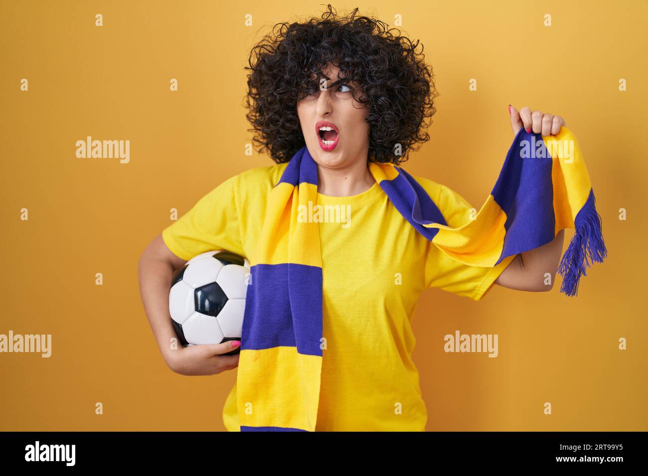 Young brunette woman with curly hair football hooligan holding ball ...