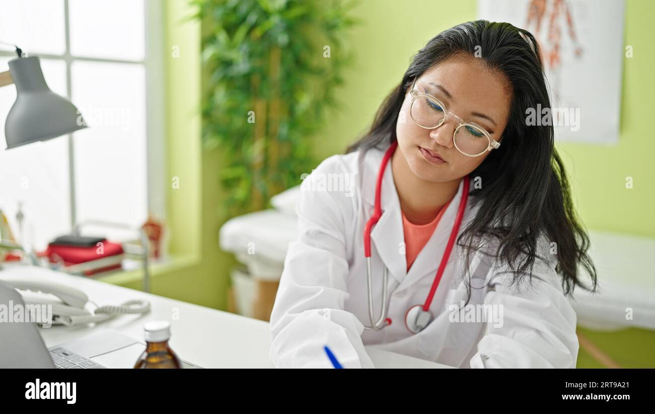 Young chinese woman doctor taking notes at the clinic Stock Photo - Alamy