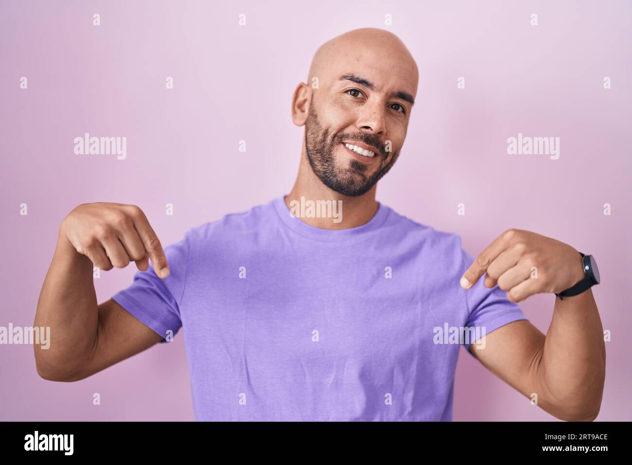 Middle age bald man standing over pink background looking confident ...