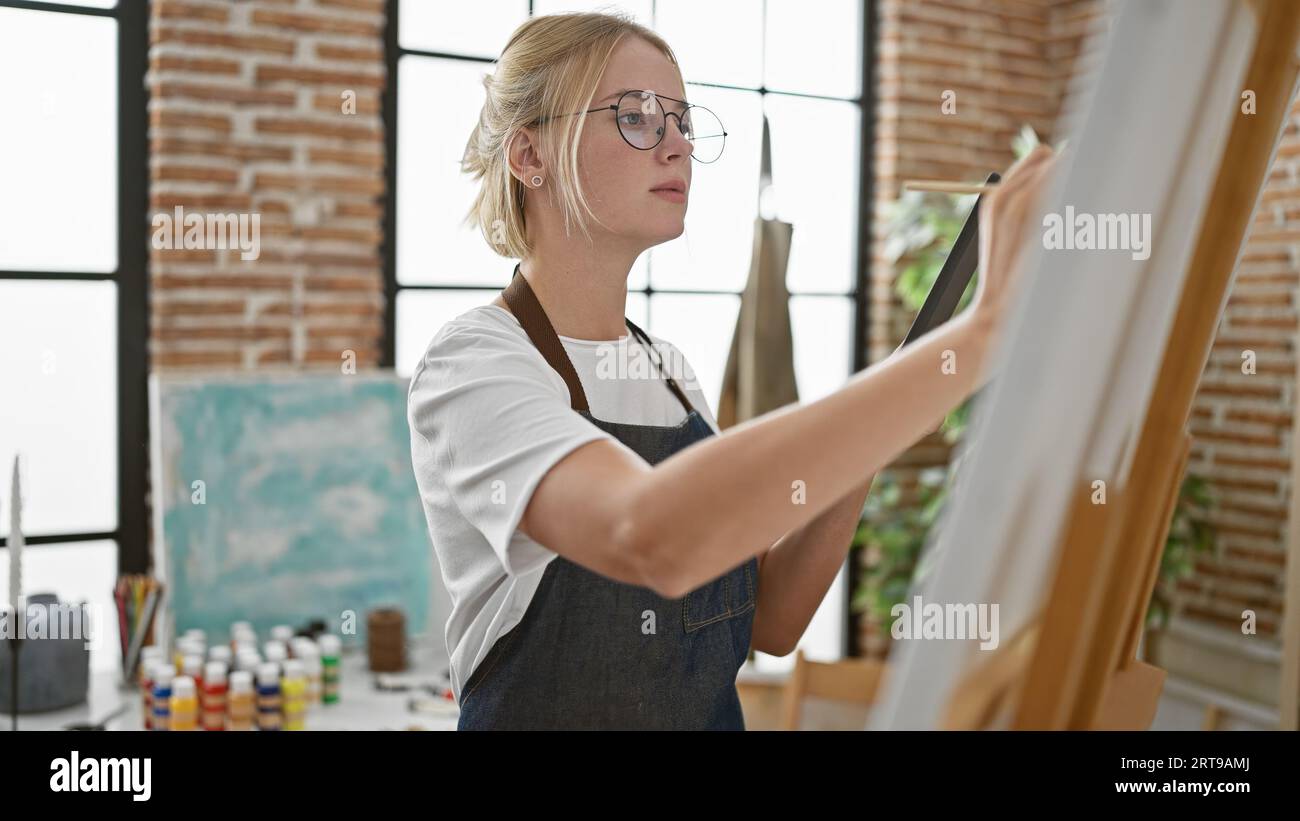 Young blonde woman artist looking touchpad drawing at art studio Stock ...