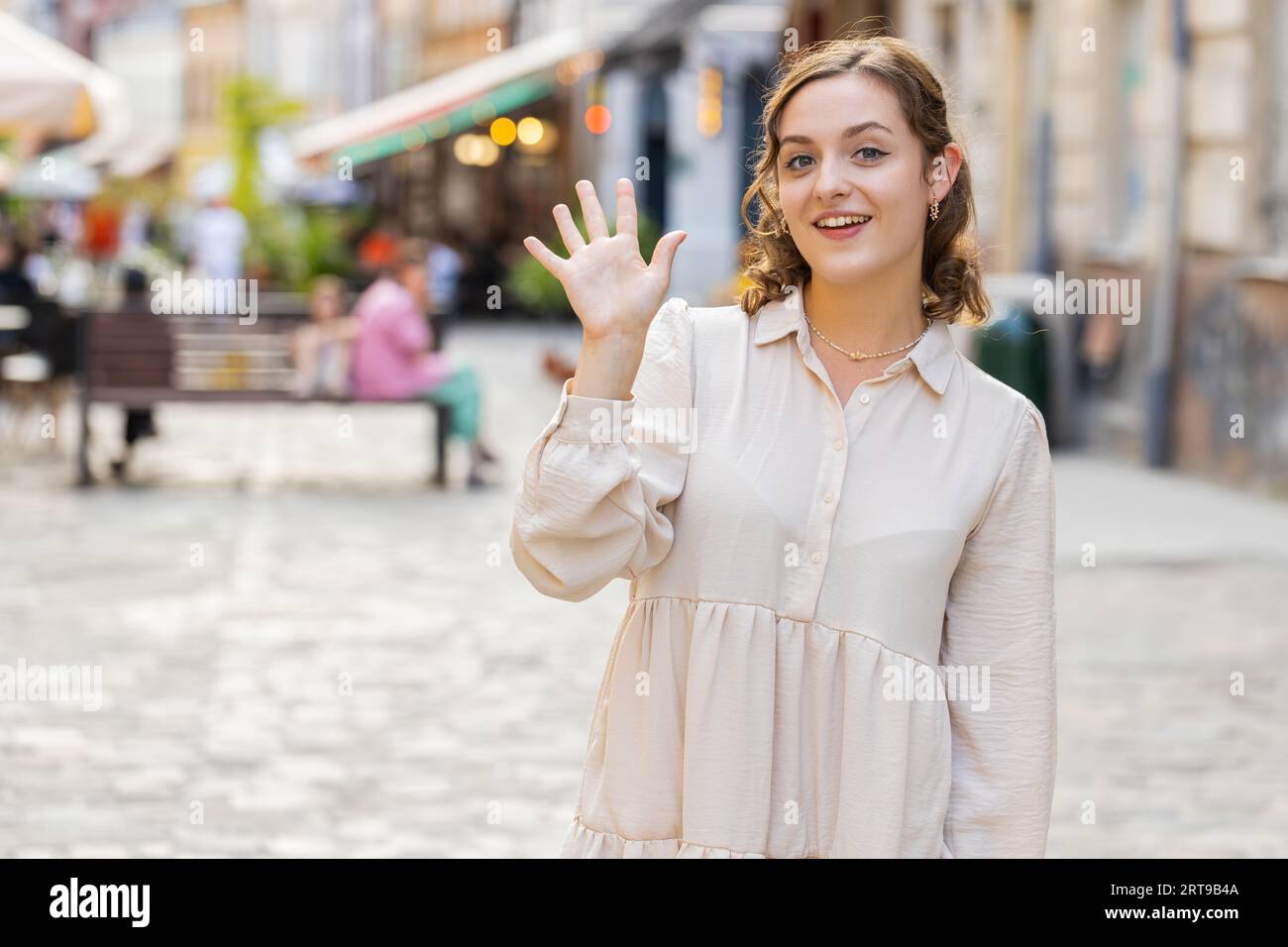 Hello. Young pretty woman smiling friendly at camera, waving hands ...