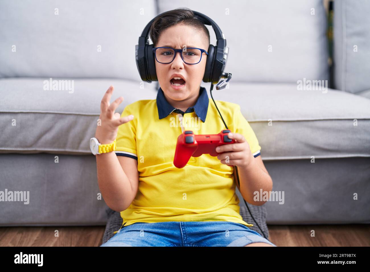 Young hispanic kid playing video game holding controller wearing ...